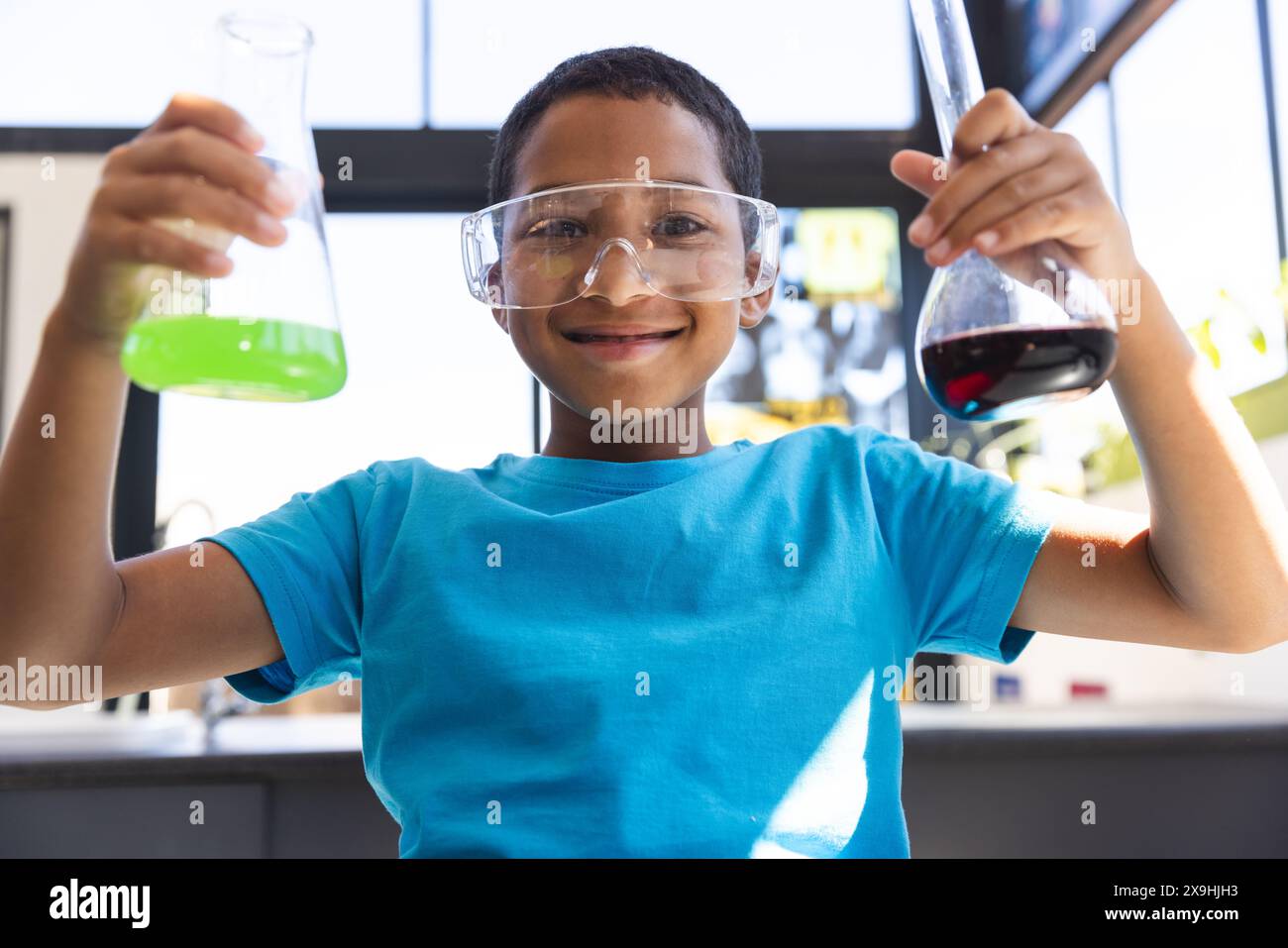Biracial boy enjoys a science experiment at school in the classroom ...