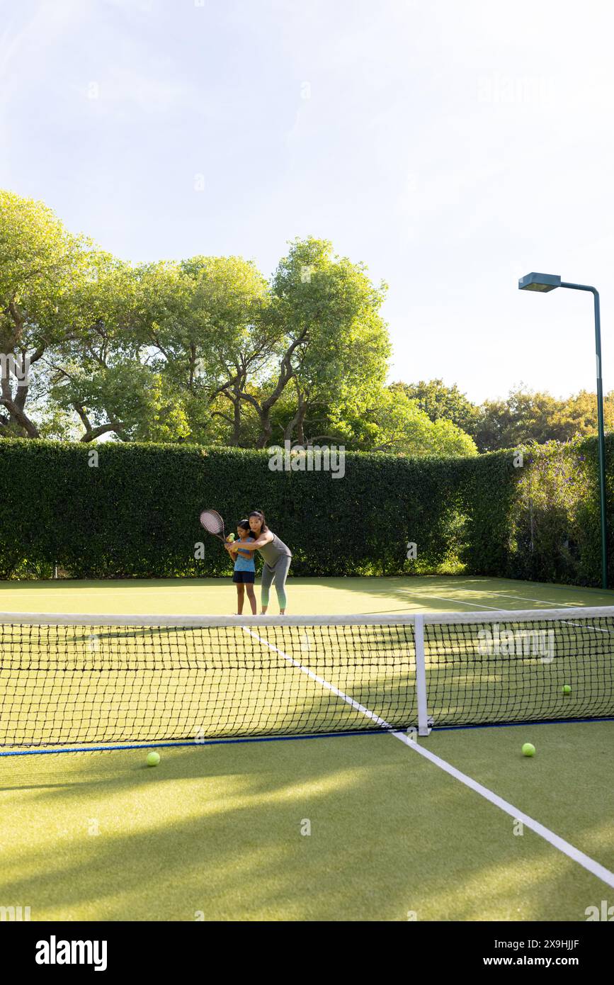 Outdoors, biracial mother and daughter learning tennis on court Stock ...