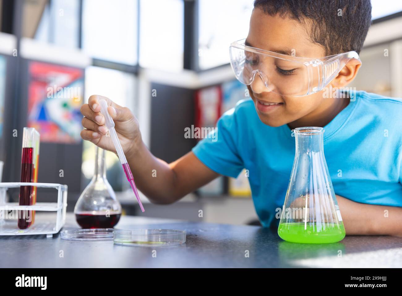 Biracial boy conducts a science experiment at school in the classroom ...
