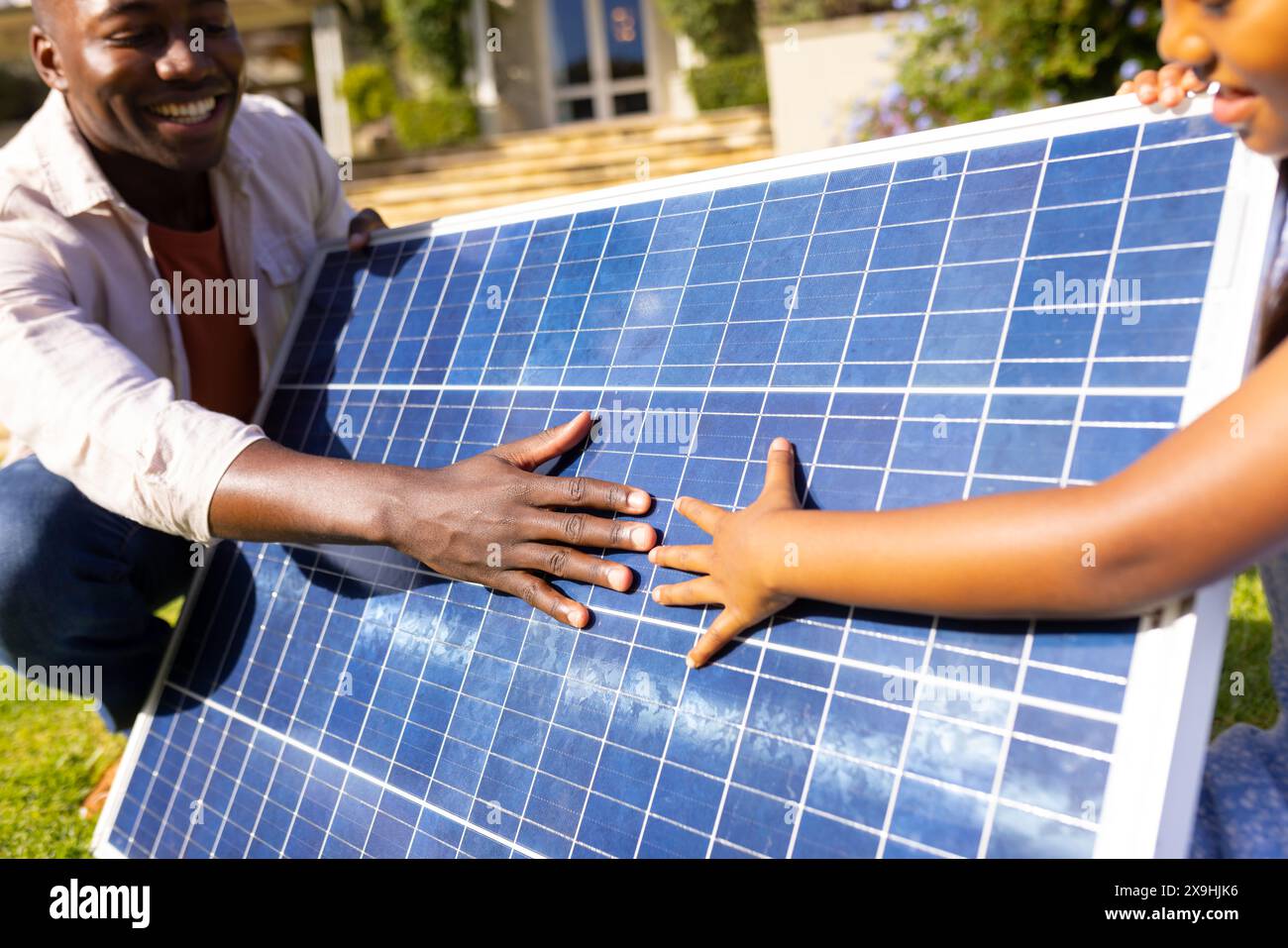 Outdoors, diverse father and daughter touching solar panel together ...