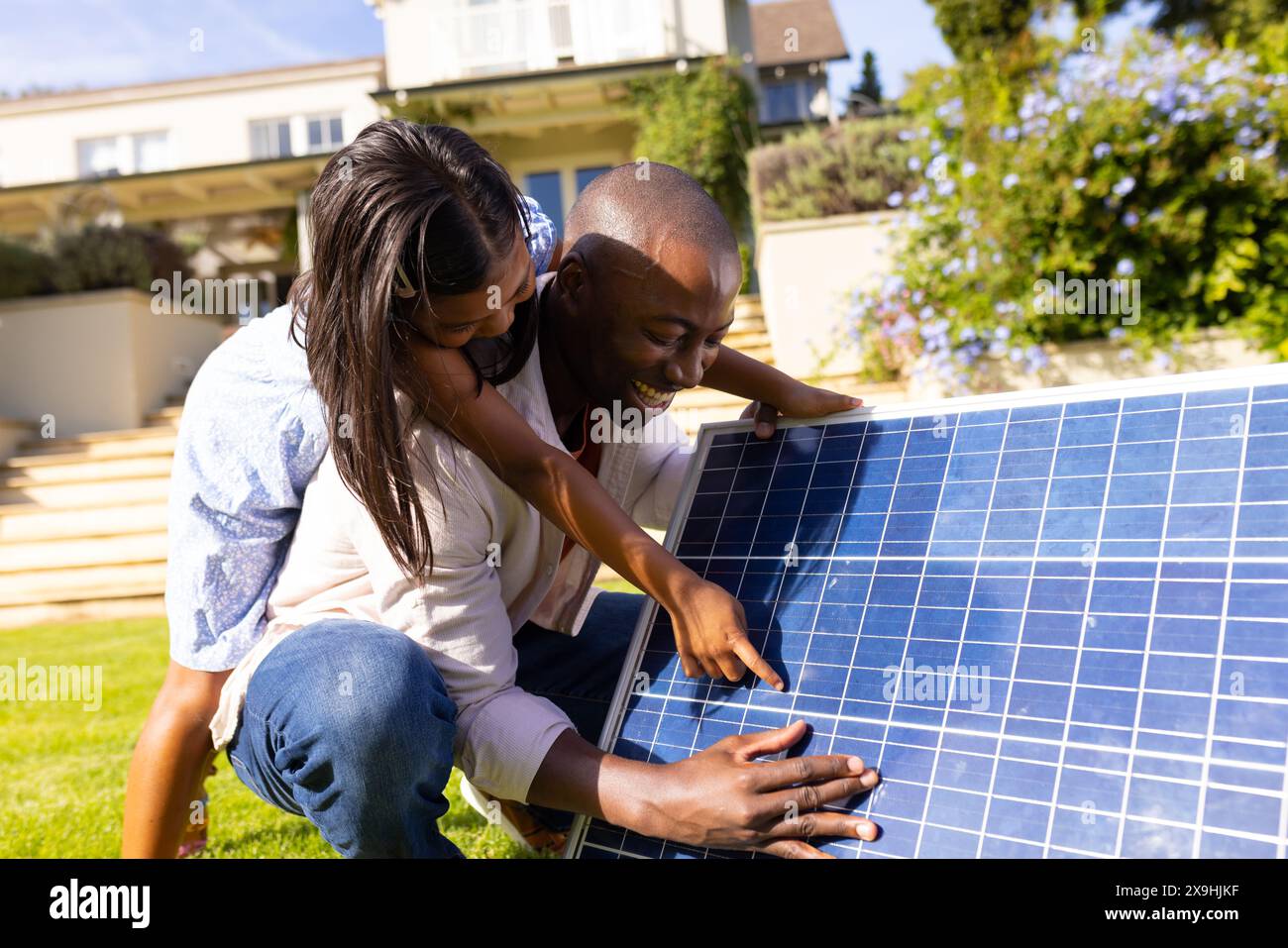 Outdoors, diverse father and daughter examining solar panel together ...