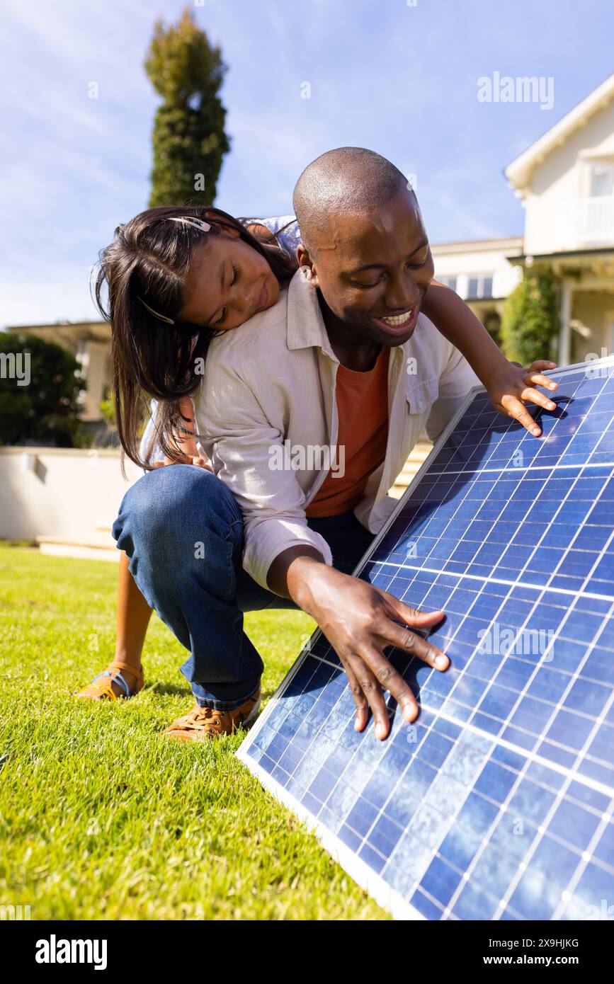 Outdoors, diverse father and daughter examining solar panel together ...