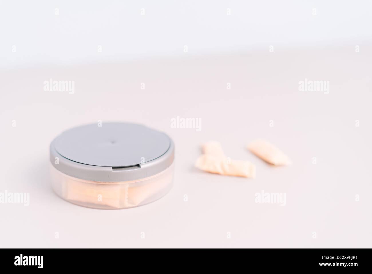 Plastic jar with fruit flavored snus sachets on a light background ...