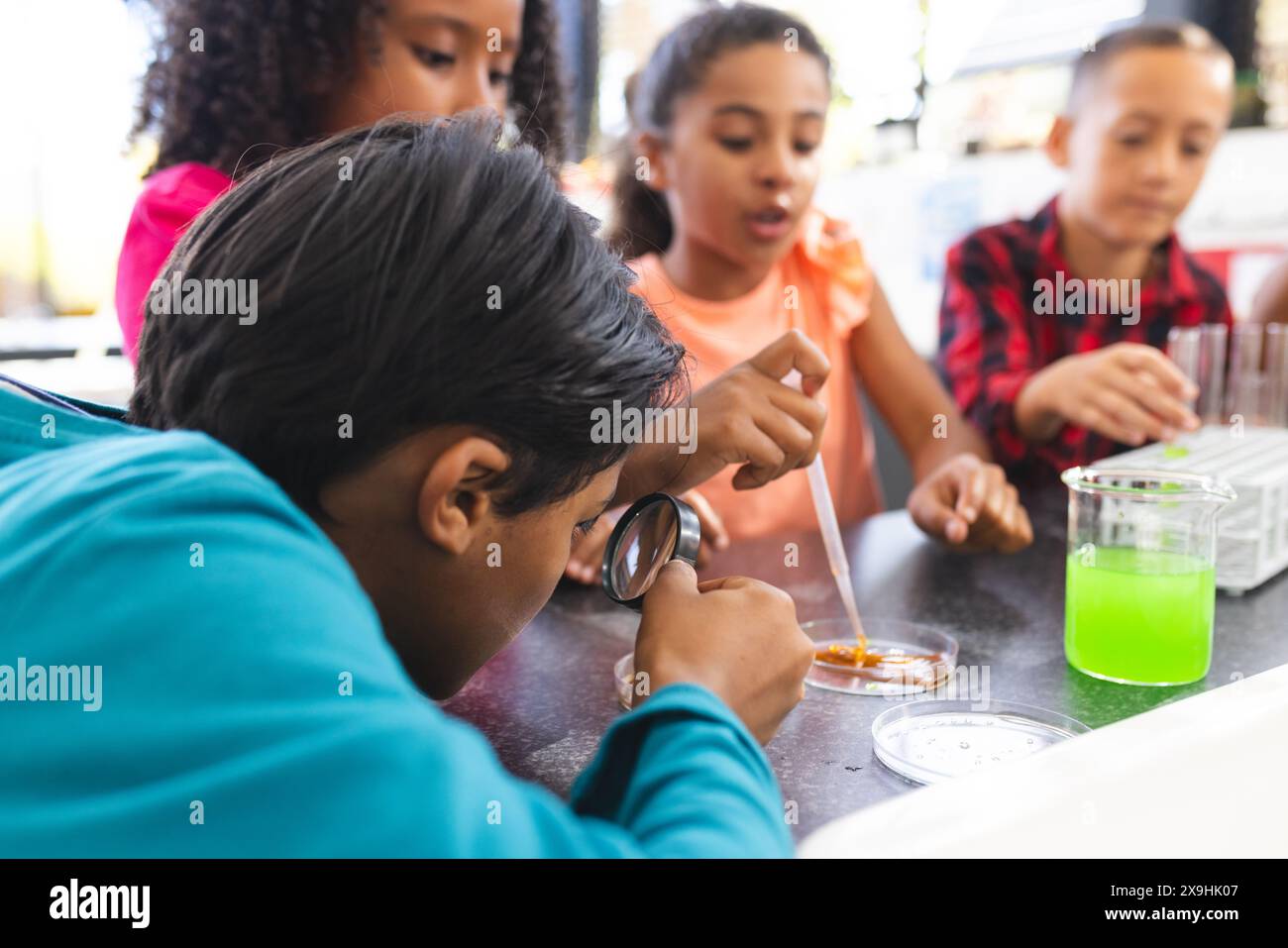 Biracial children engage in a science experiment at school, one ...