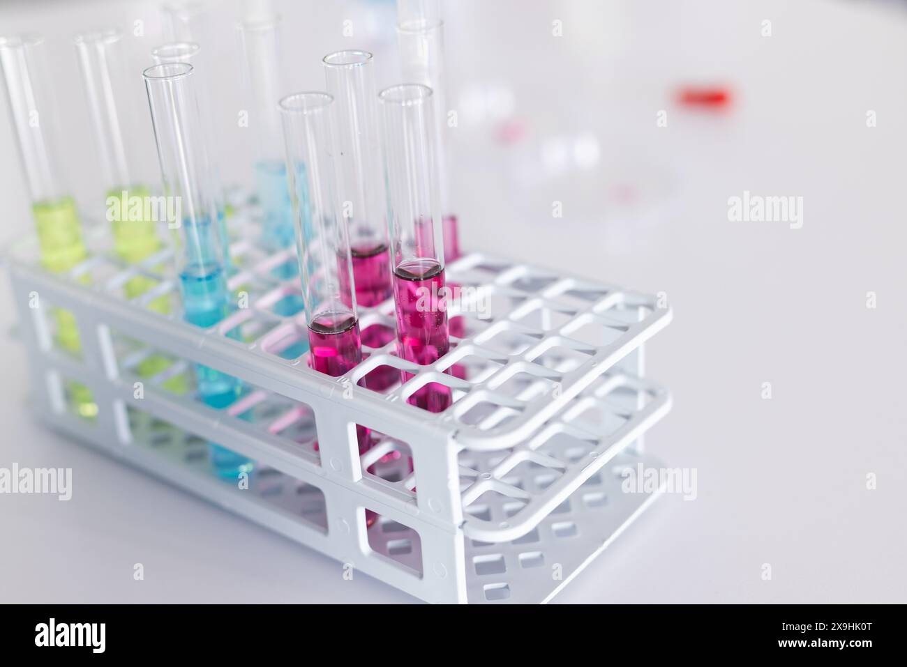 Test tubes filled with colorful liquids in a lab rack, with copy space ...