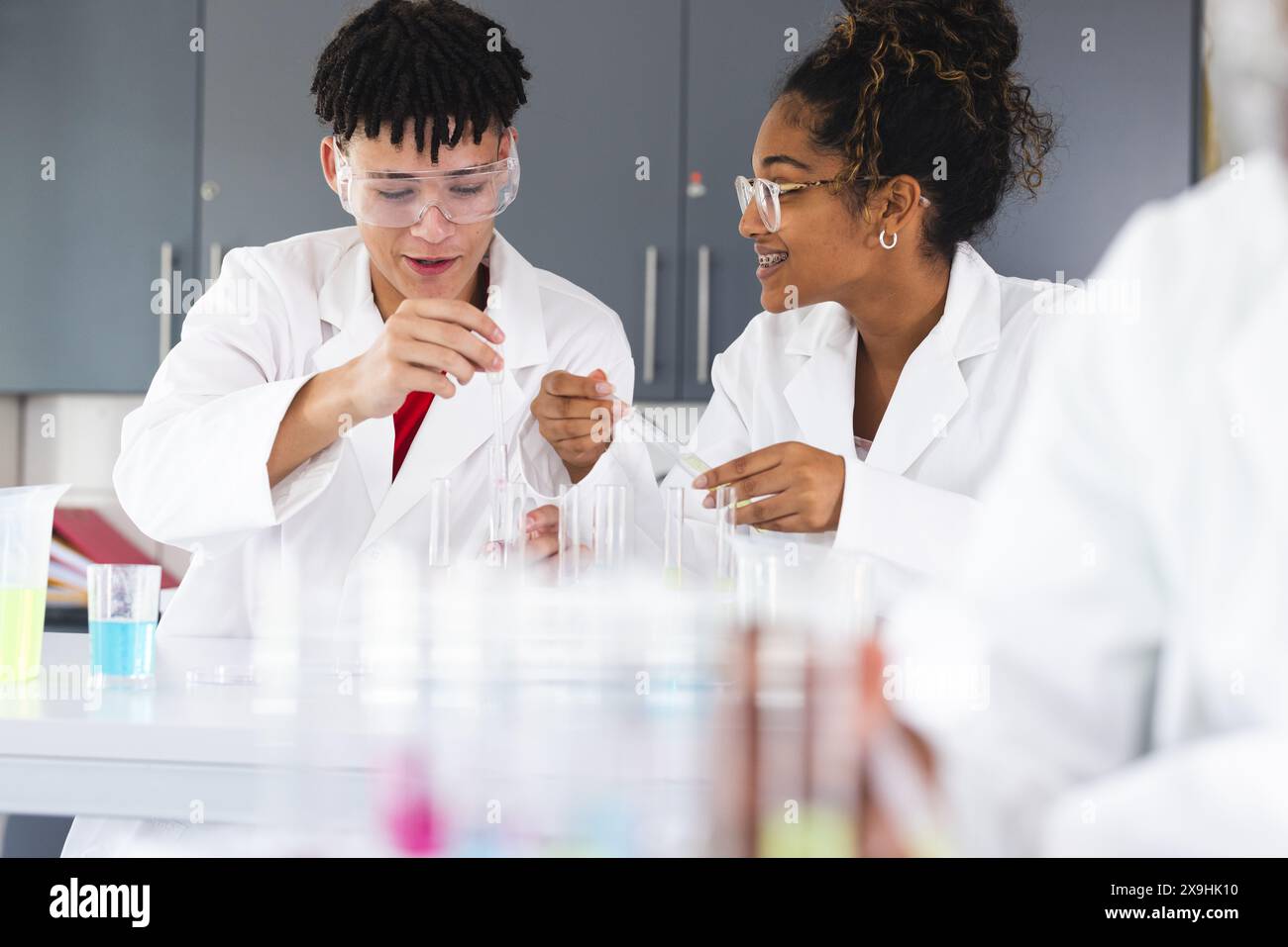 Teenage biracial students conduct an experiment in a high school lab ...