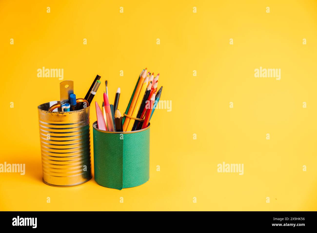 Recycling tin cans for containers with pencils and pens on yellow ...