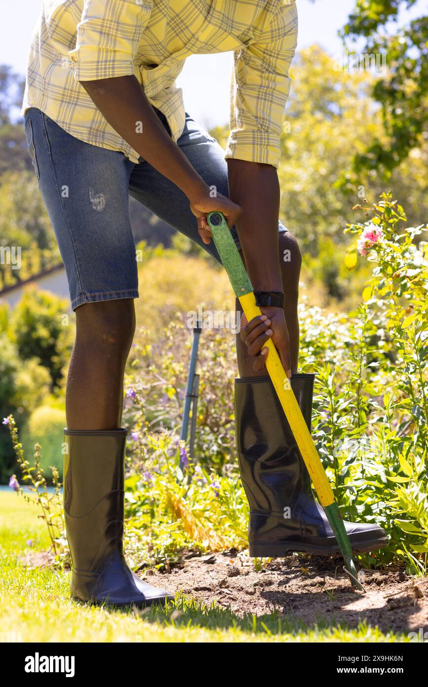 An African American young male digging outside, wearing boots and ...