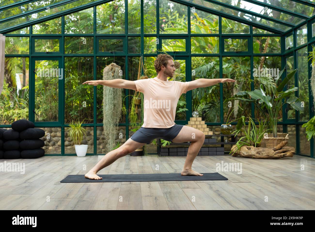 Glass house studio captures Caucasian male yoga instructor practicing ...