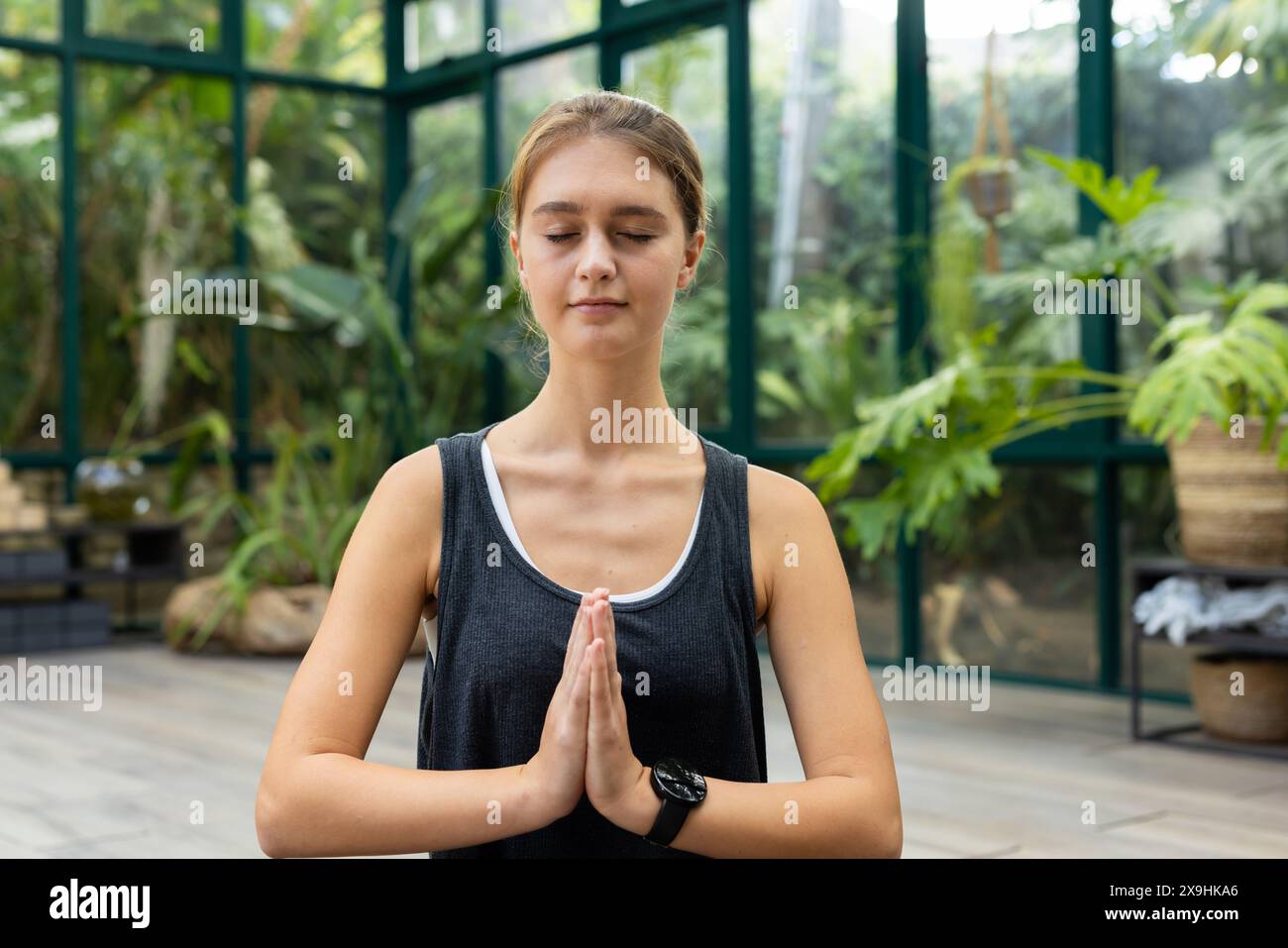 Glass house studio shows caucasian woman in black top meditating with ...