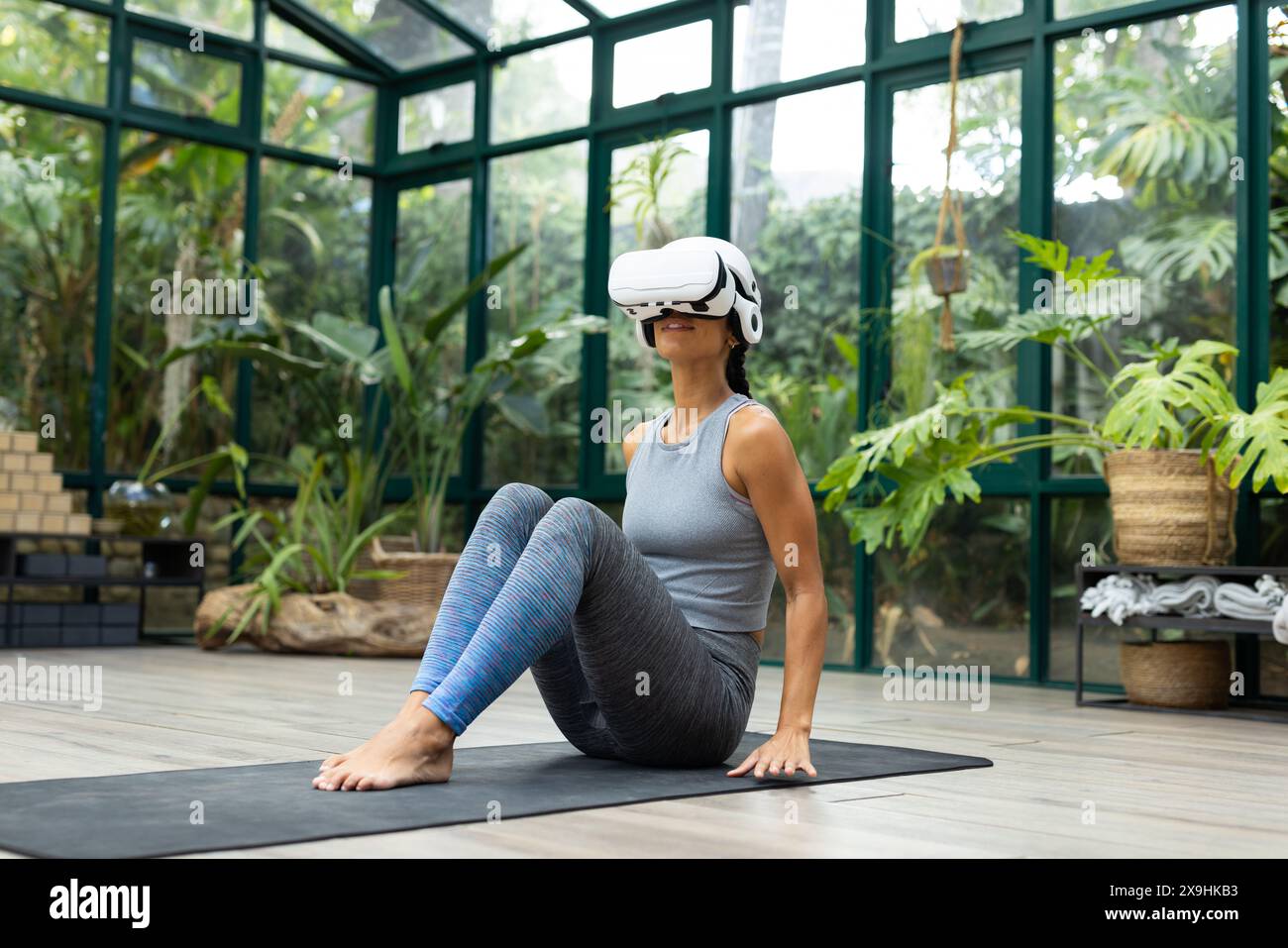 Pacific Islander woman, yoga teacher in VR, sits on mat at Glass House ...