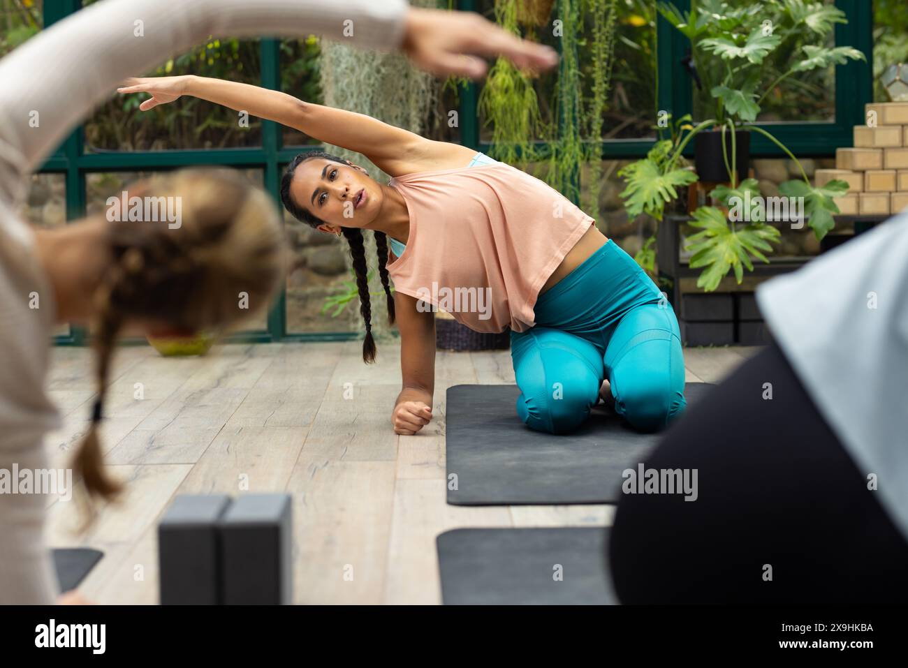 At glass house studio, diverse yoga students and instructor, guiding. A ...