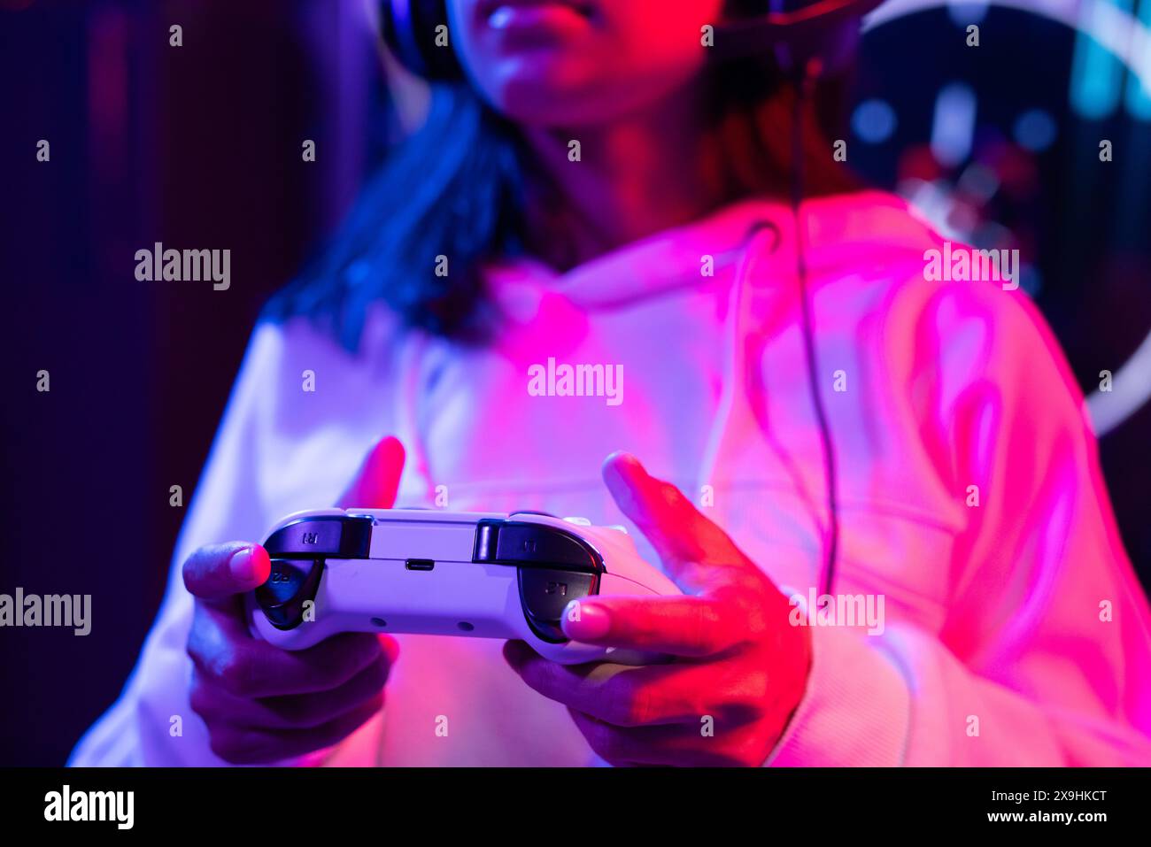 A biracial young girl holding gaming controller at home, focusing on ...