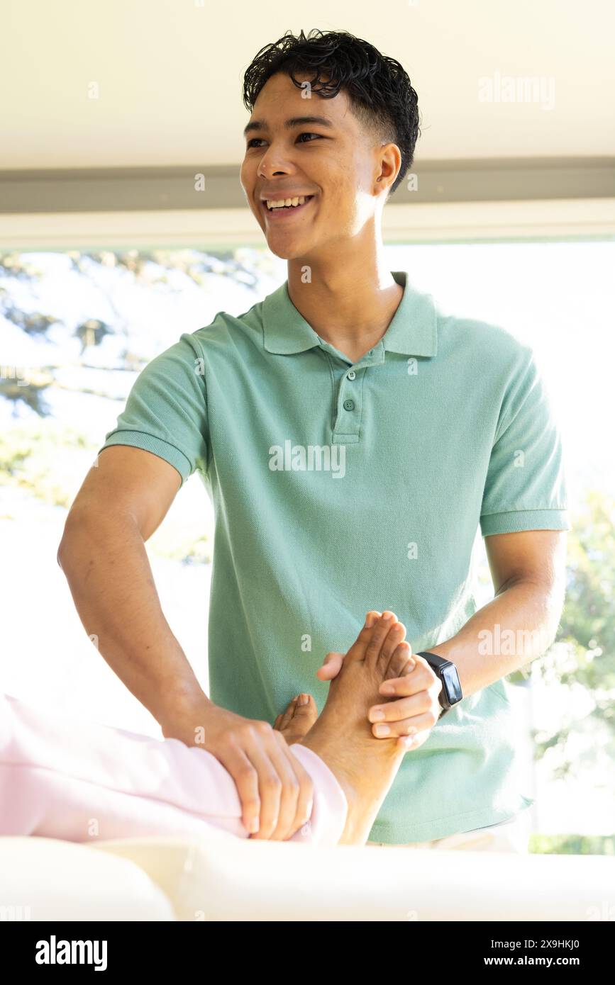 At home, biracial male physiotherapist aids senior female patient with ...