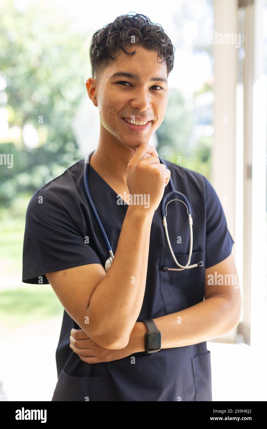 Biracial male nurse in navy scrubs with stethoscope, smiling ...
