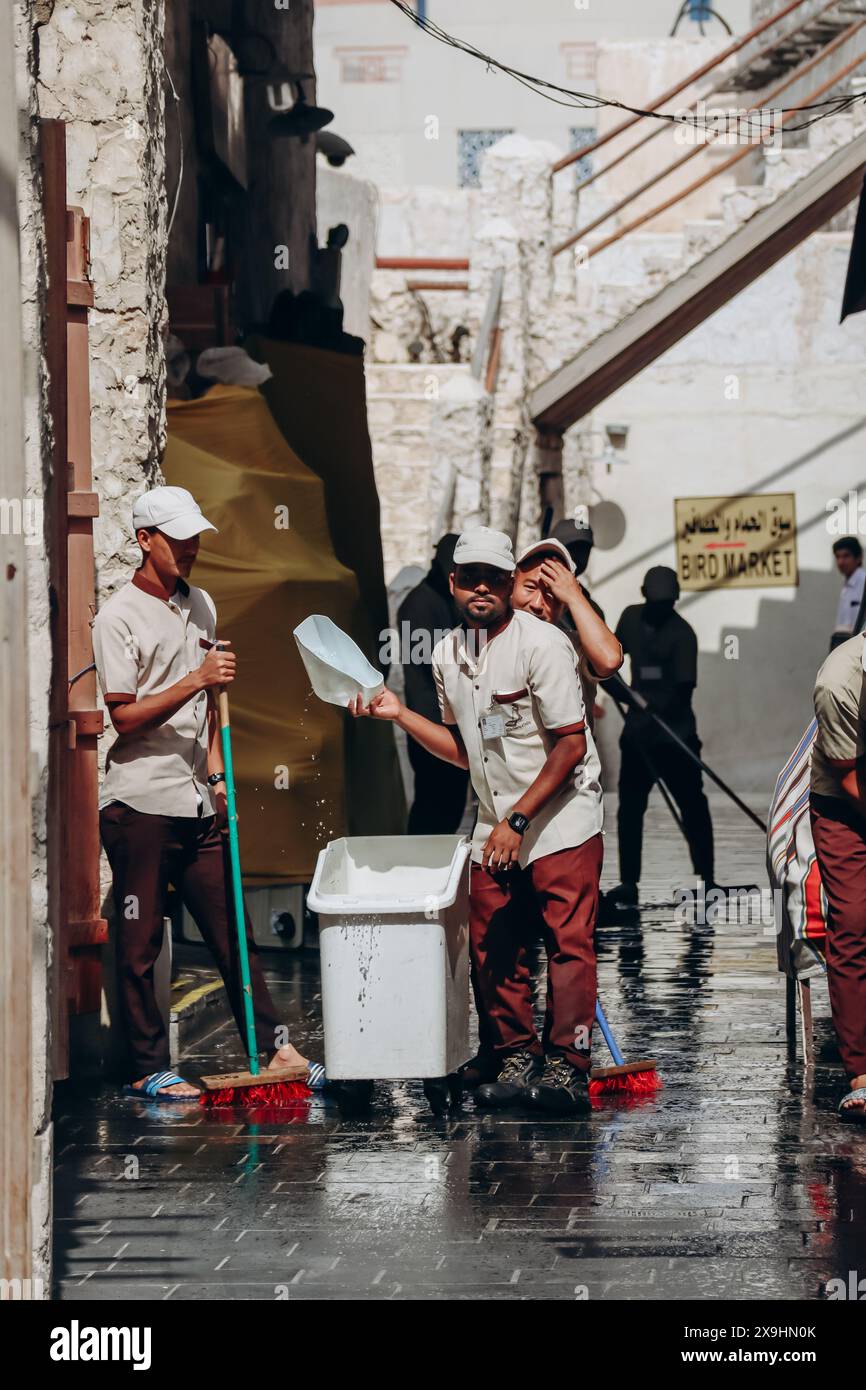 Doha, Qatar - 1 May 2024: A group of cleaners wash the streets during ...