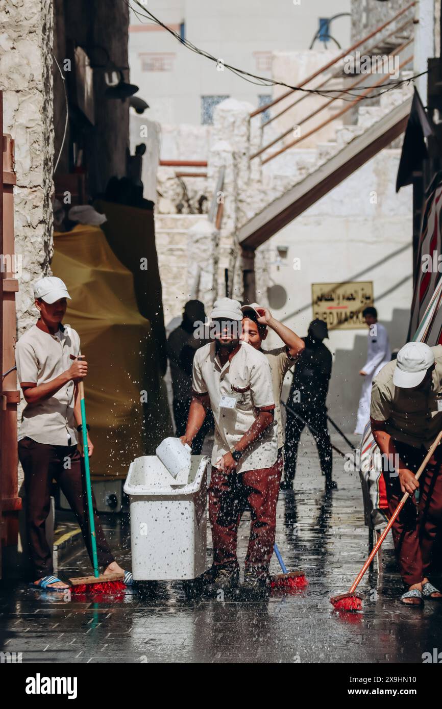 Doha, Qatar - 1 May 2024: A group of cleaners wash the streets during ...