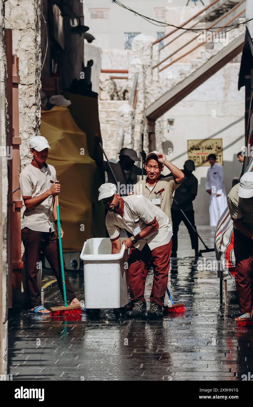 Doha, Qatar - 1 May 2024: A group of cleaners wash the streets during ...
