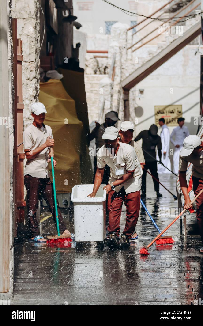 Doha, Qatar - 1 May 2024: A group of cleaners wash the streets during ...