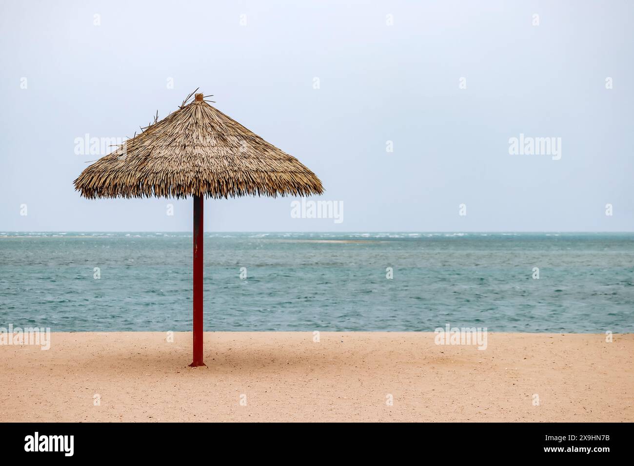 Straw umbrella on the beach in Doha on a cloudy day Stock Photo - Alamy