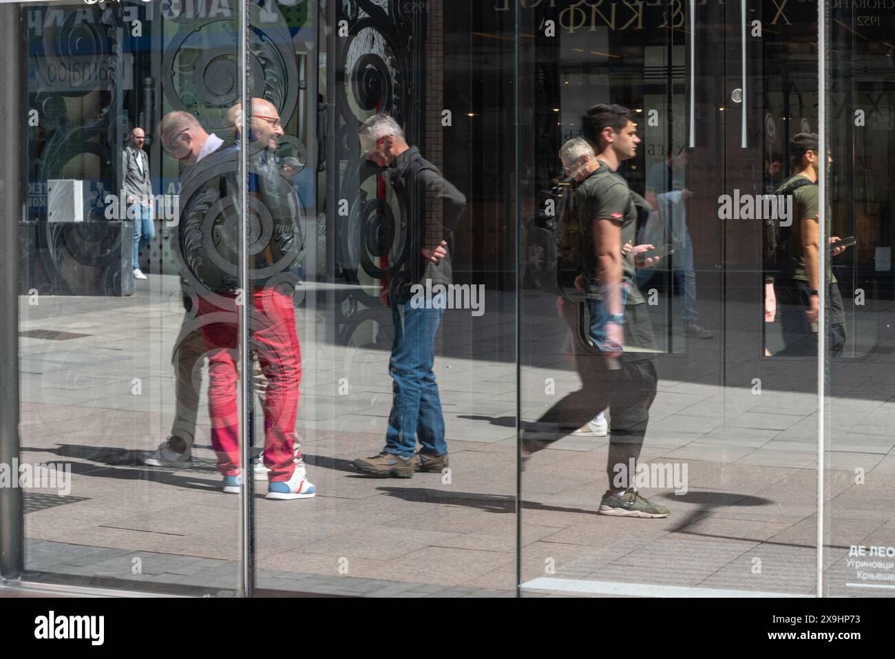 Unusual and slightly abstract reflection of shoppers in a shop window ...
