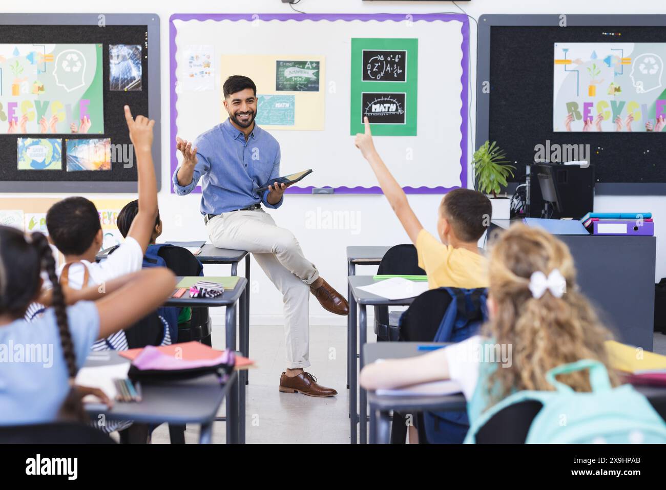Young Asian male teacher teaching a diverse group of children in a ...