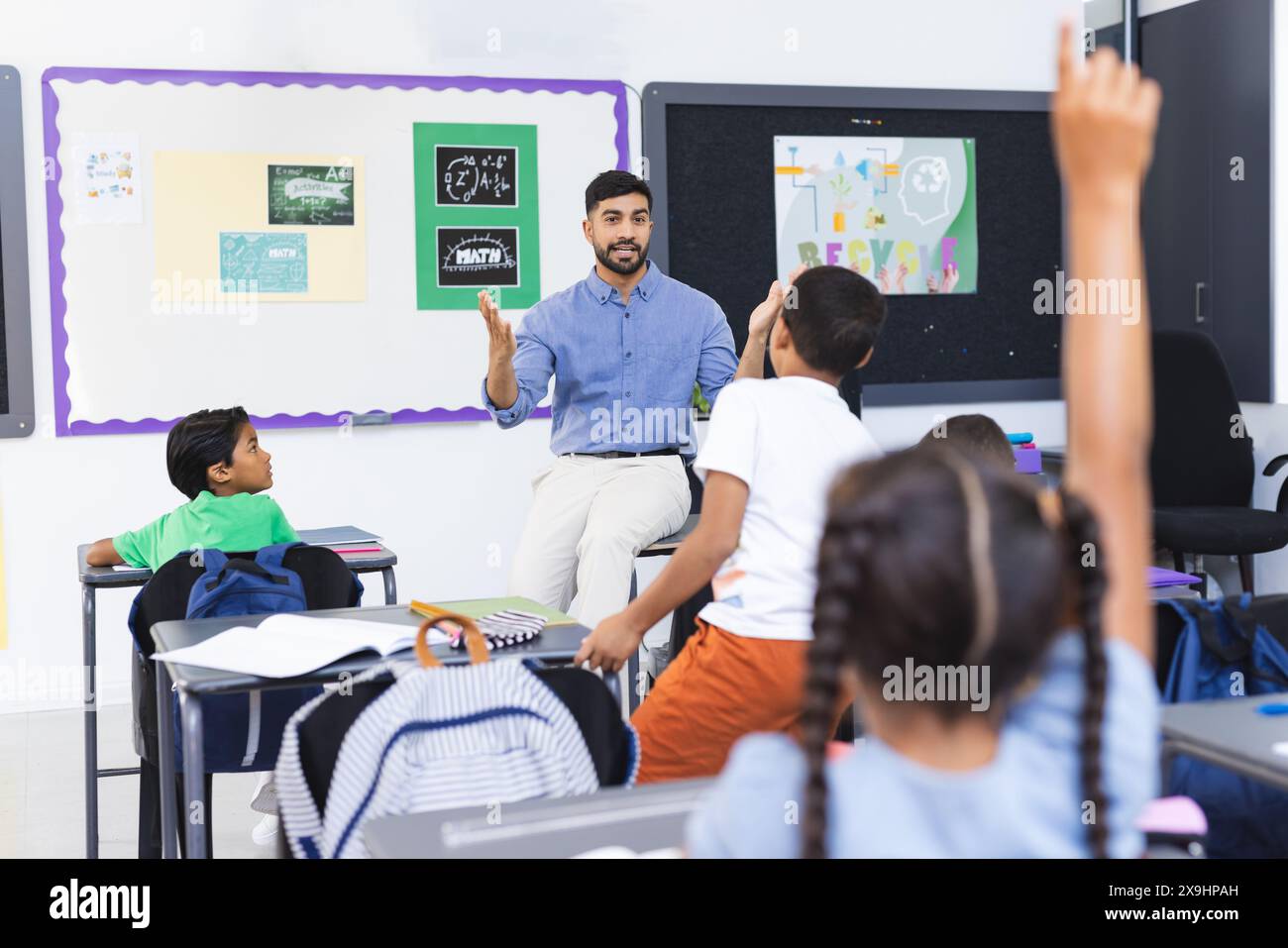 Young Asian male teacher teaching a diverse group of children in a ...