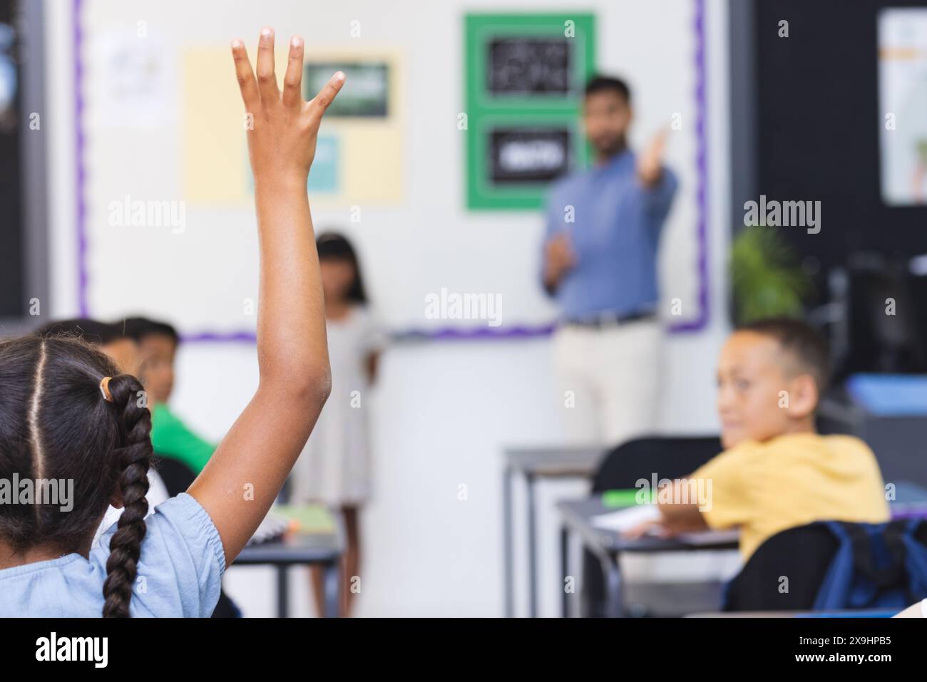 In school, young Asian male teacher stands by a board in the classroom ...