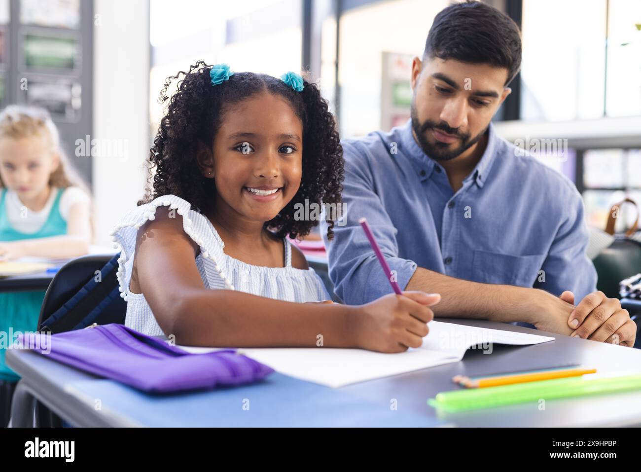 Young Asian male teacher teaching a biracial girl in a school classroom setting Stock Photo - Alamy