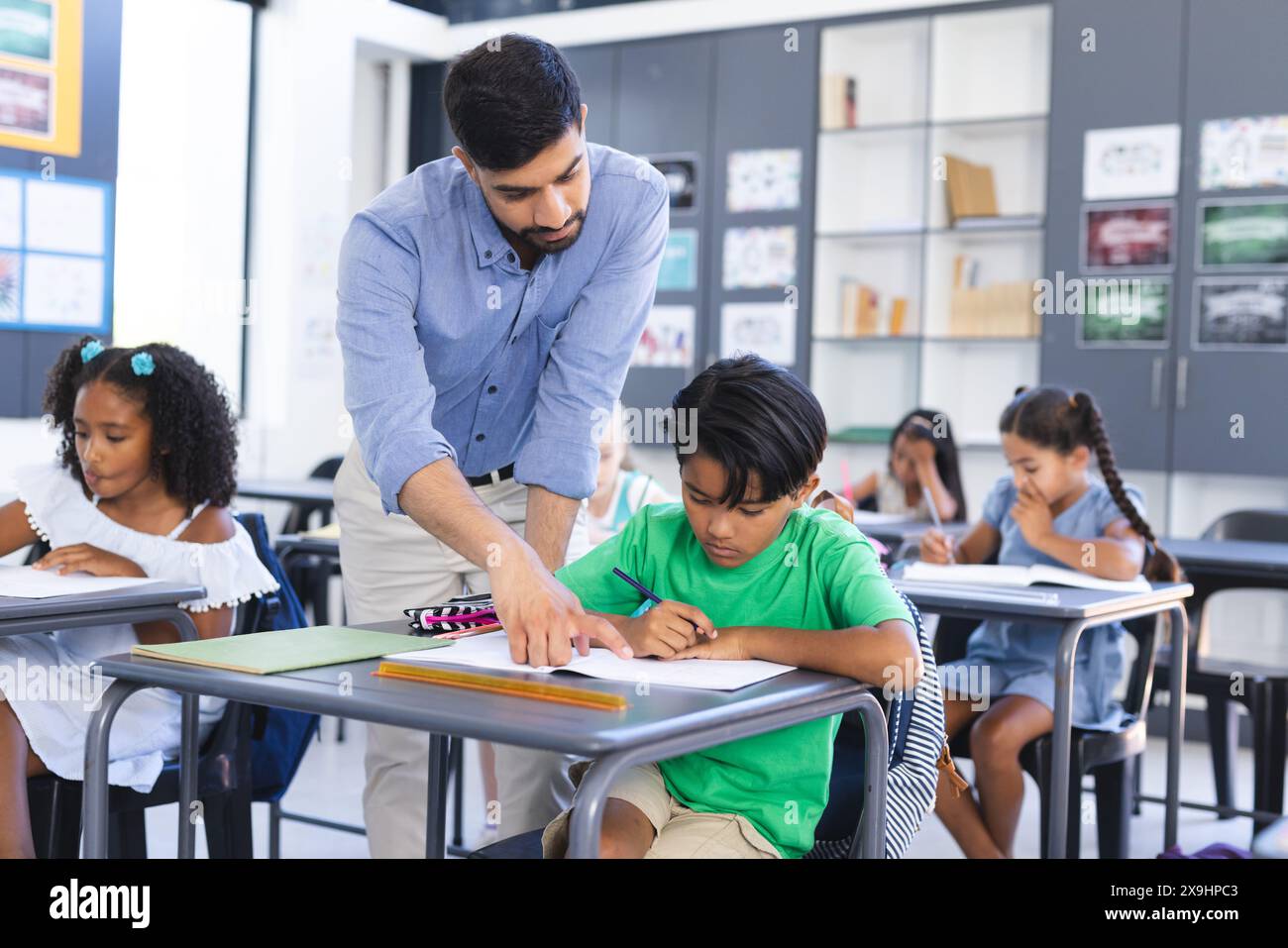 Young Asian male teacher teaching a biracial boy in a school classroom setting Stock Photo - Alamy