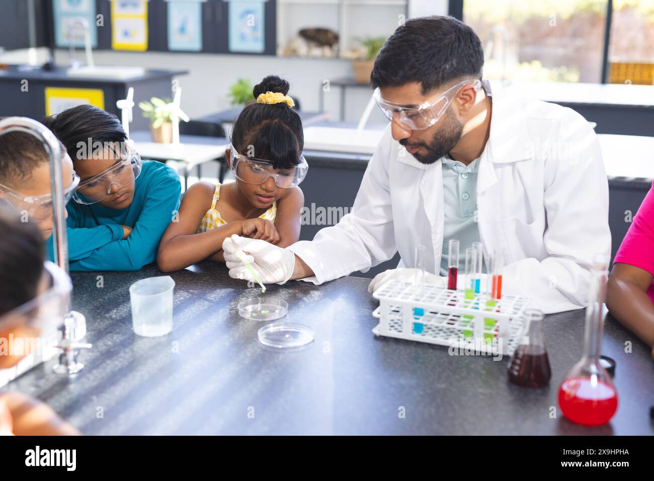 Young Asian male teacher conducts a science experiment with diverse ...