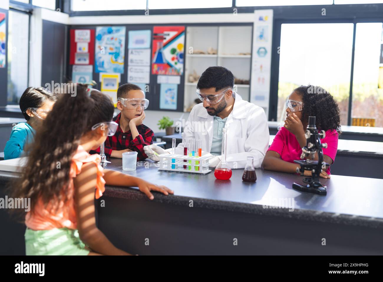 Young Asian male teacher conducts a science experiment with a diverse ...