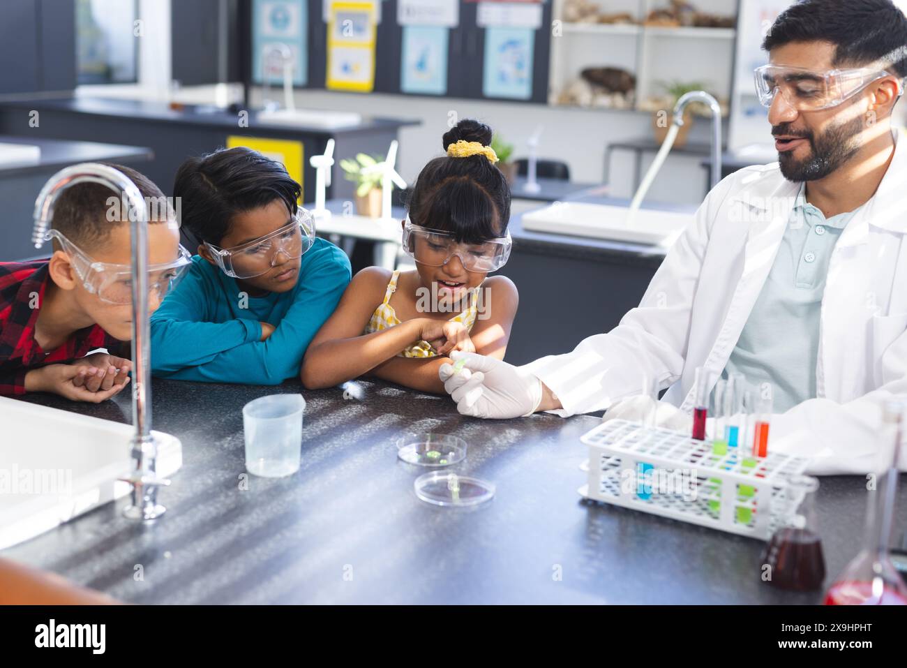 In school, Asian male teacher showing chemistry signs to young biracial ...