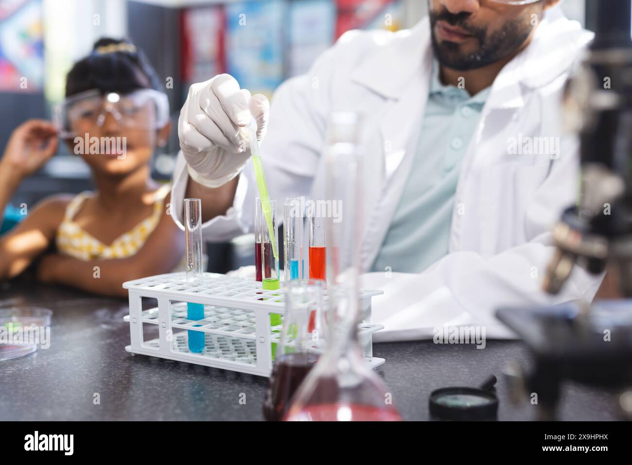 Young Asian male teacher conducting an experiment in school, biracial ...