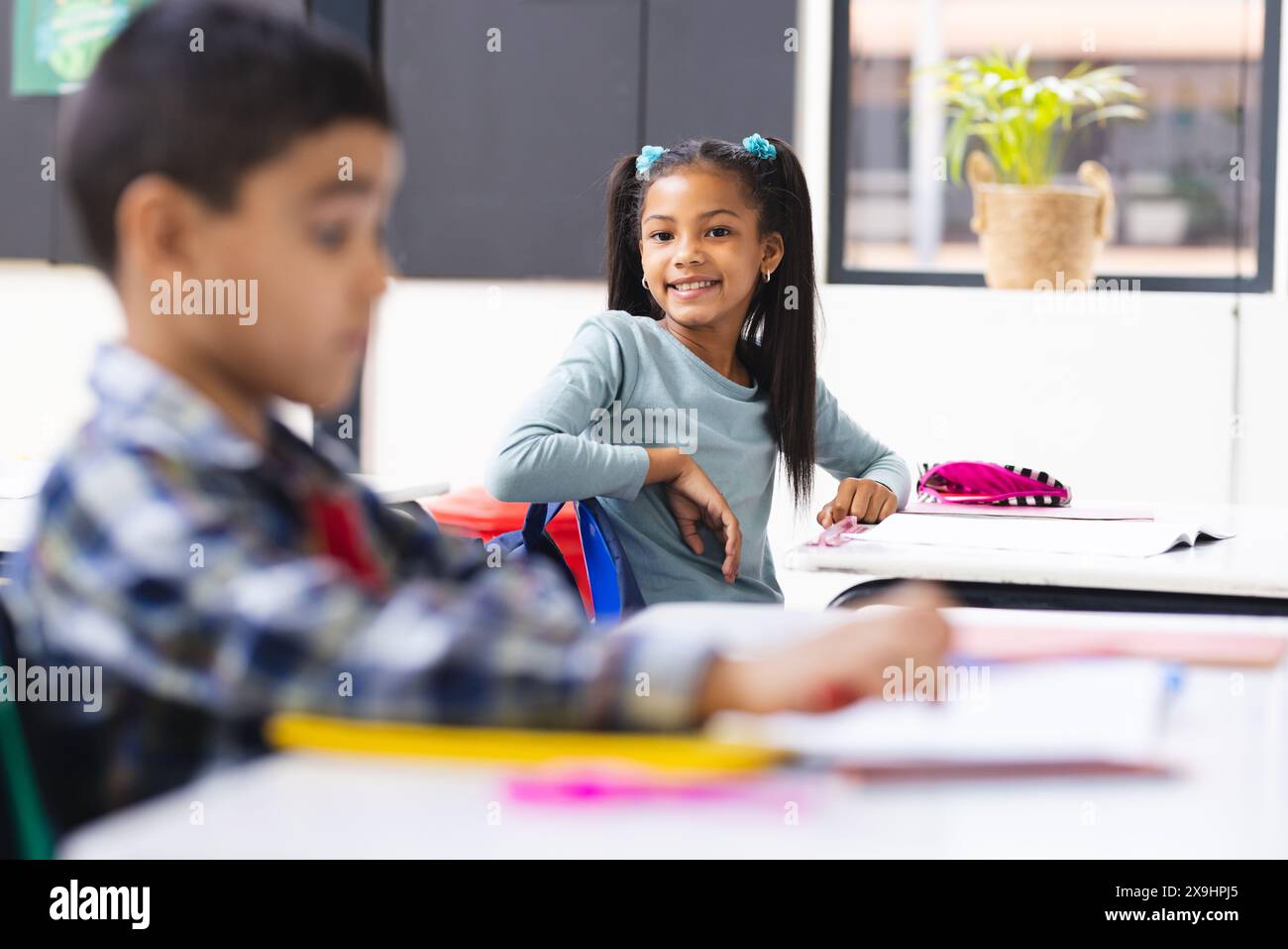 In school, young biracial boy and girl focusing on their studies in ...