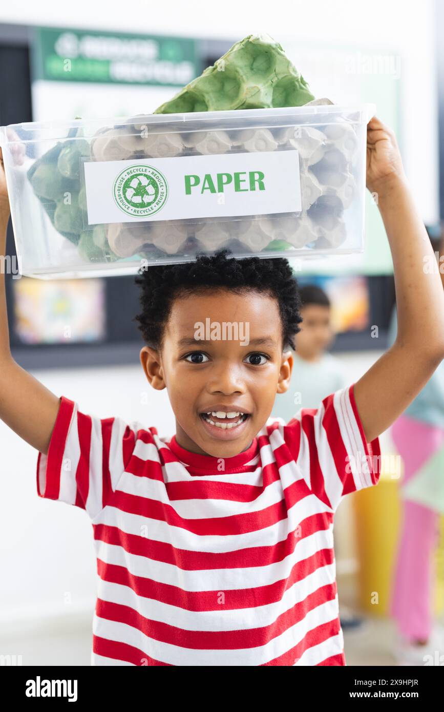 Young African American boy holds recycle bin above his head in ...
