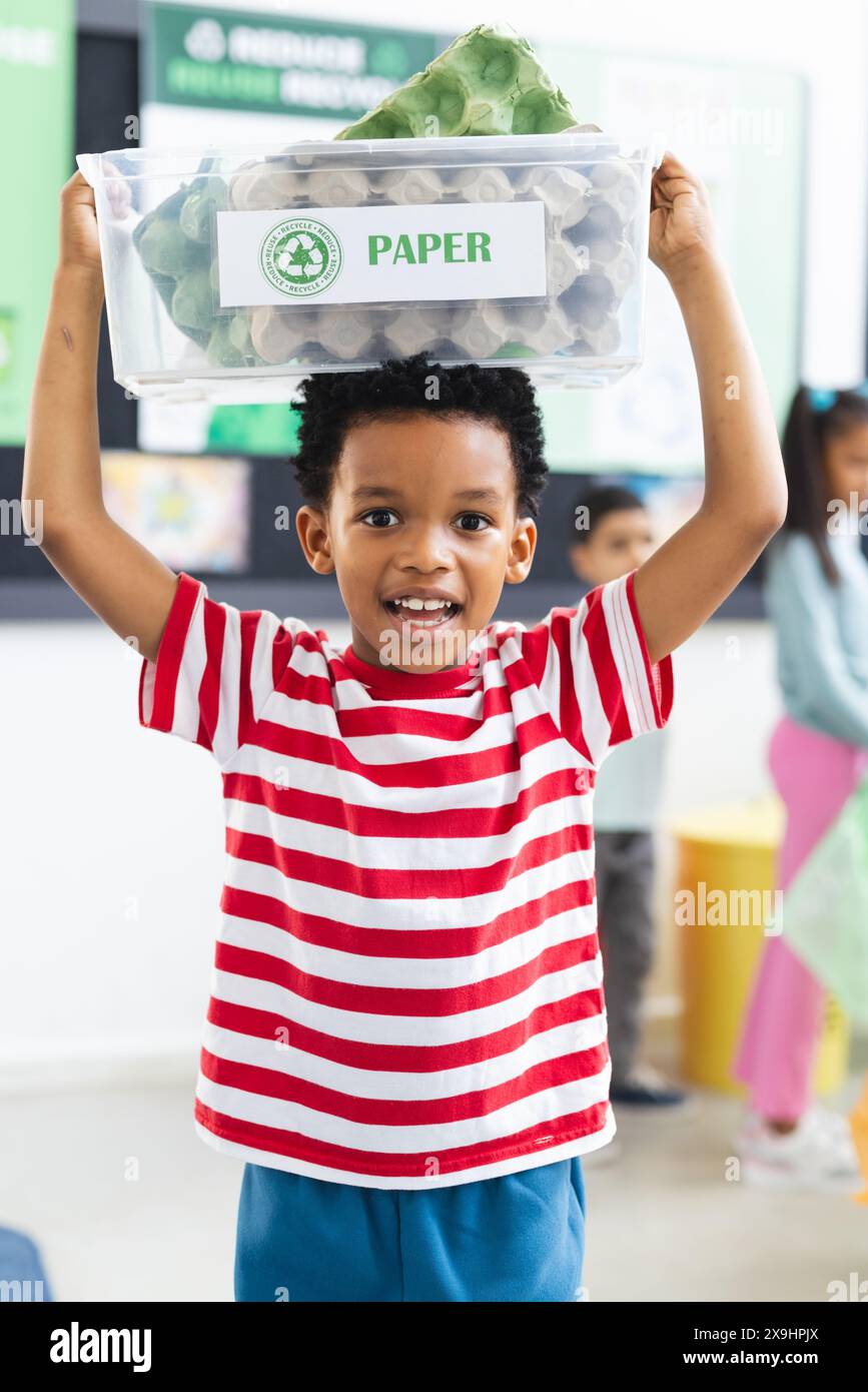 In school, young African American boy holding up paper recycling bin in ...