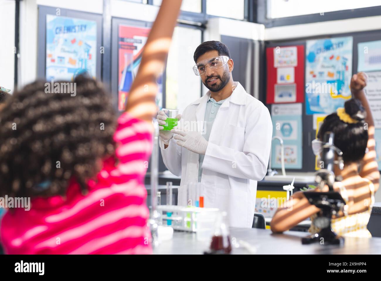 Young Asian male teacher demonstrates a science experiment to children ...