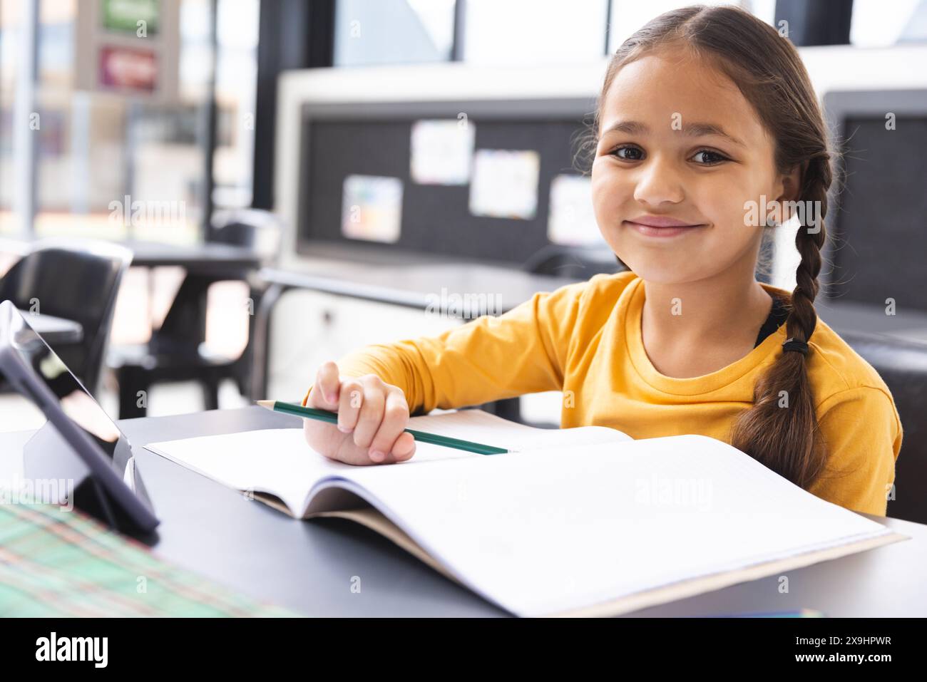 In school, in a classroom, a young biracial girl with light brown skin ...