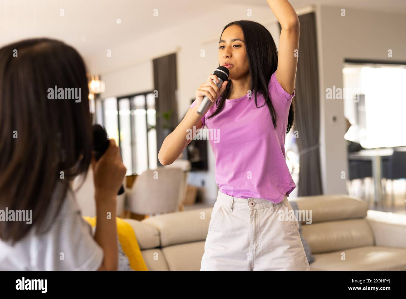 Two biracial young sisters singing and recording at home Stock Photo ...