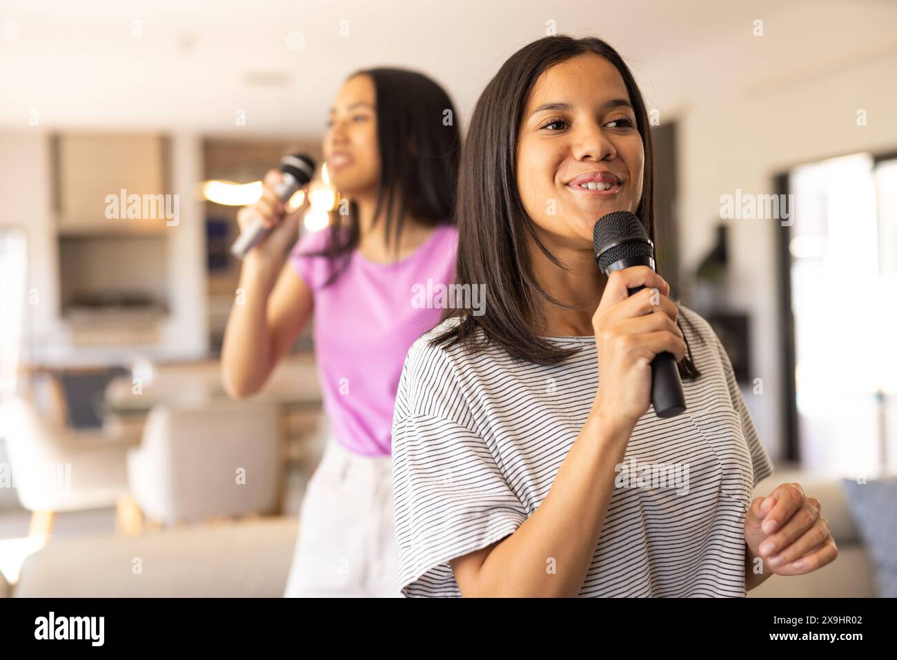 Biracial young sisters, singing with microphones at home, showcase long ...