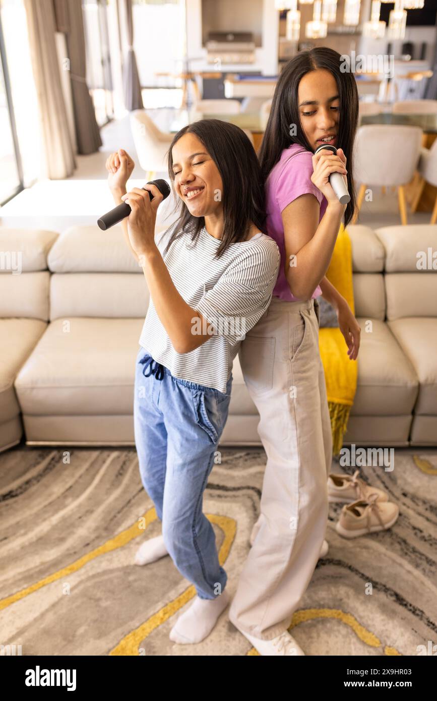 Biracial young sisters singing into microphones at home Stock Photo - Alamy