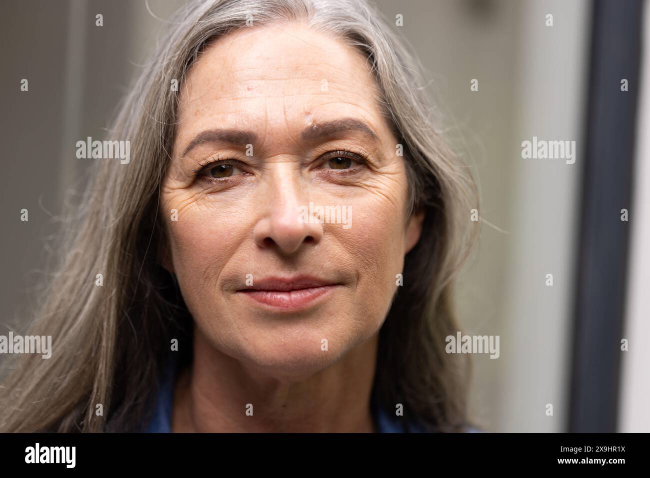 At home, senior Caucasian female with long gray hair and wrinkles on ...