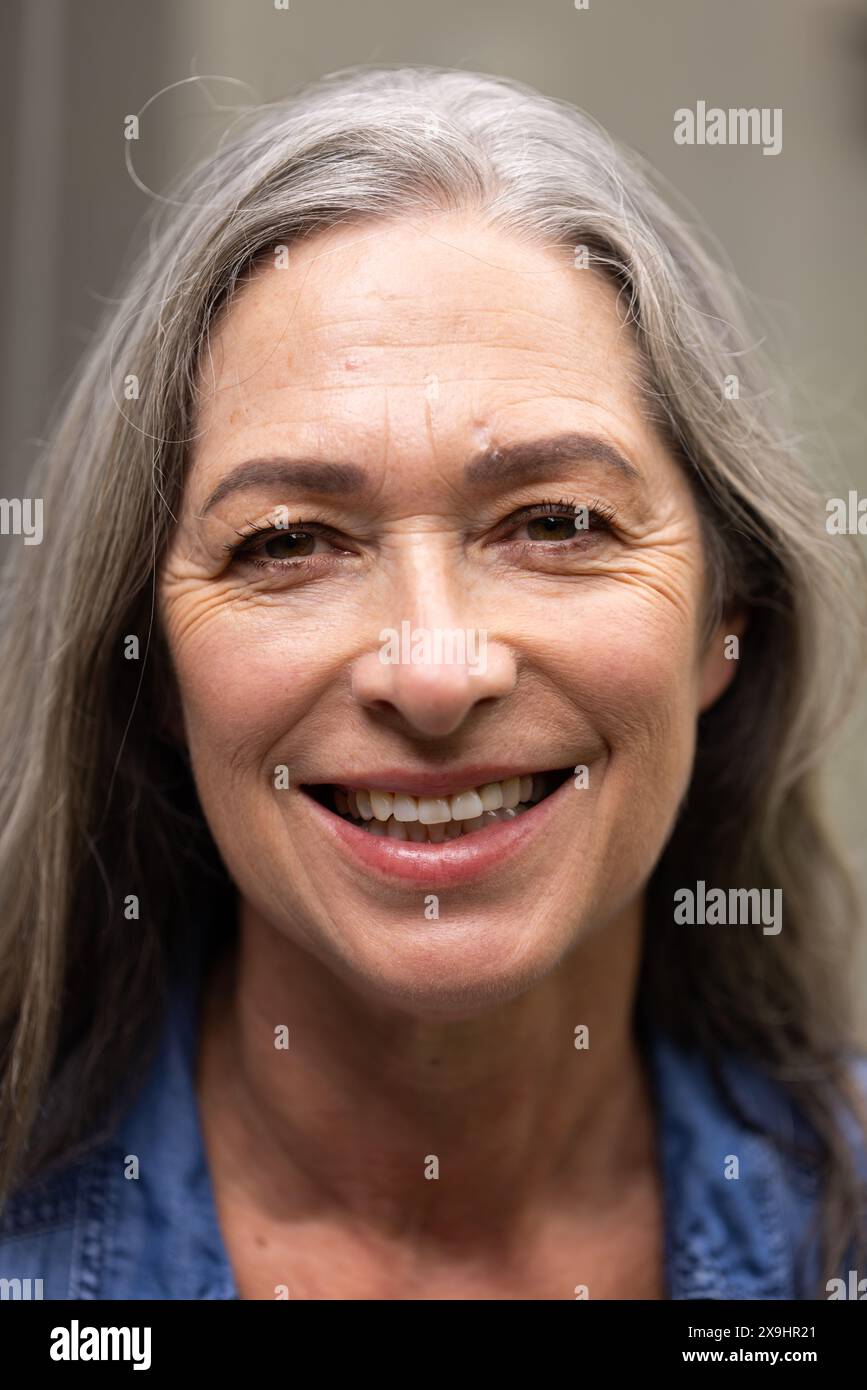 At home, senior Caucasian female with long gray hair and wrinkles ...