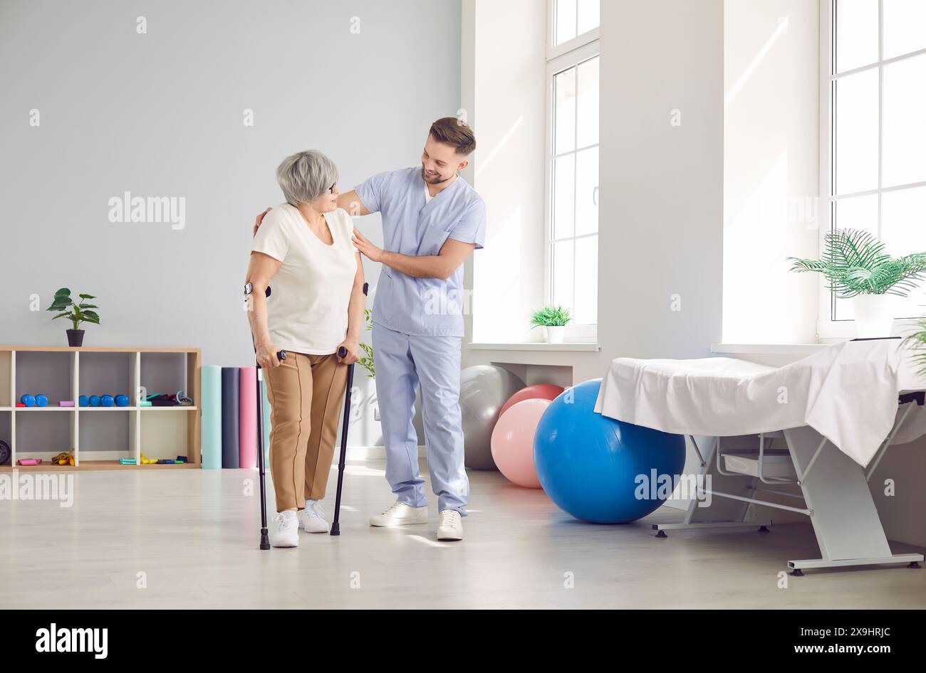 Young male caregiver, nurse helping to disabled aged female patient to ...