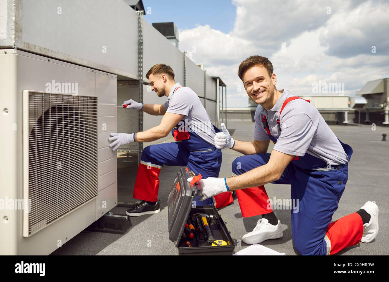 Technician installing air conditioner and looking cheerful at camera ...