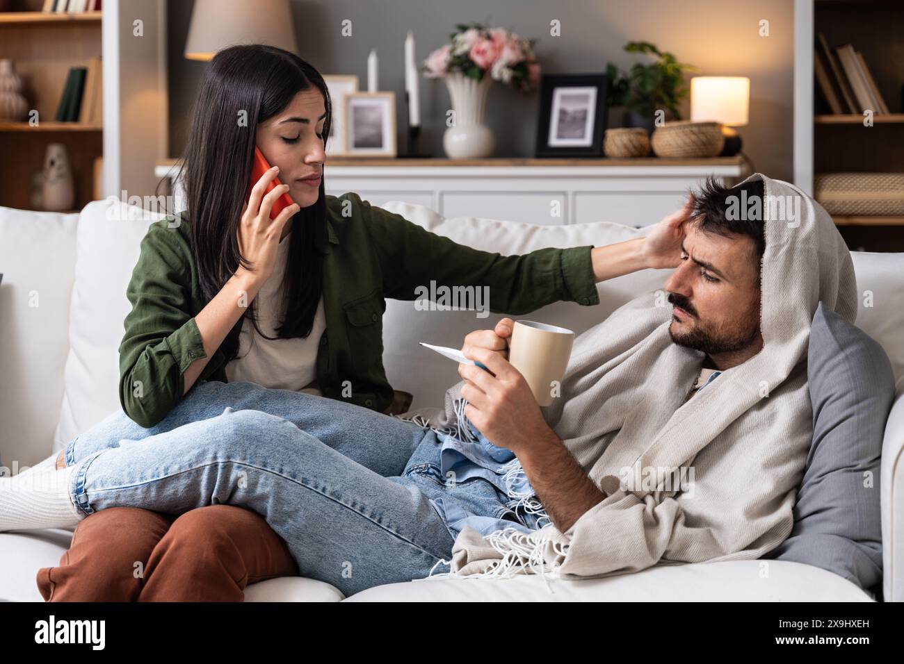 Young woman helping and treats her sick man at home who is wrapped in a ...