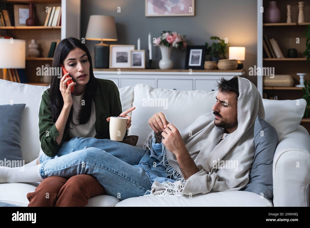 Young woman helping and treats her sick man at home who is wrapped in a ...