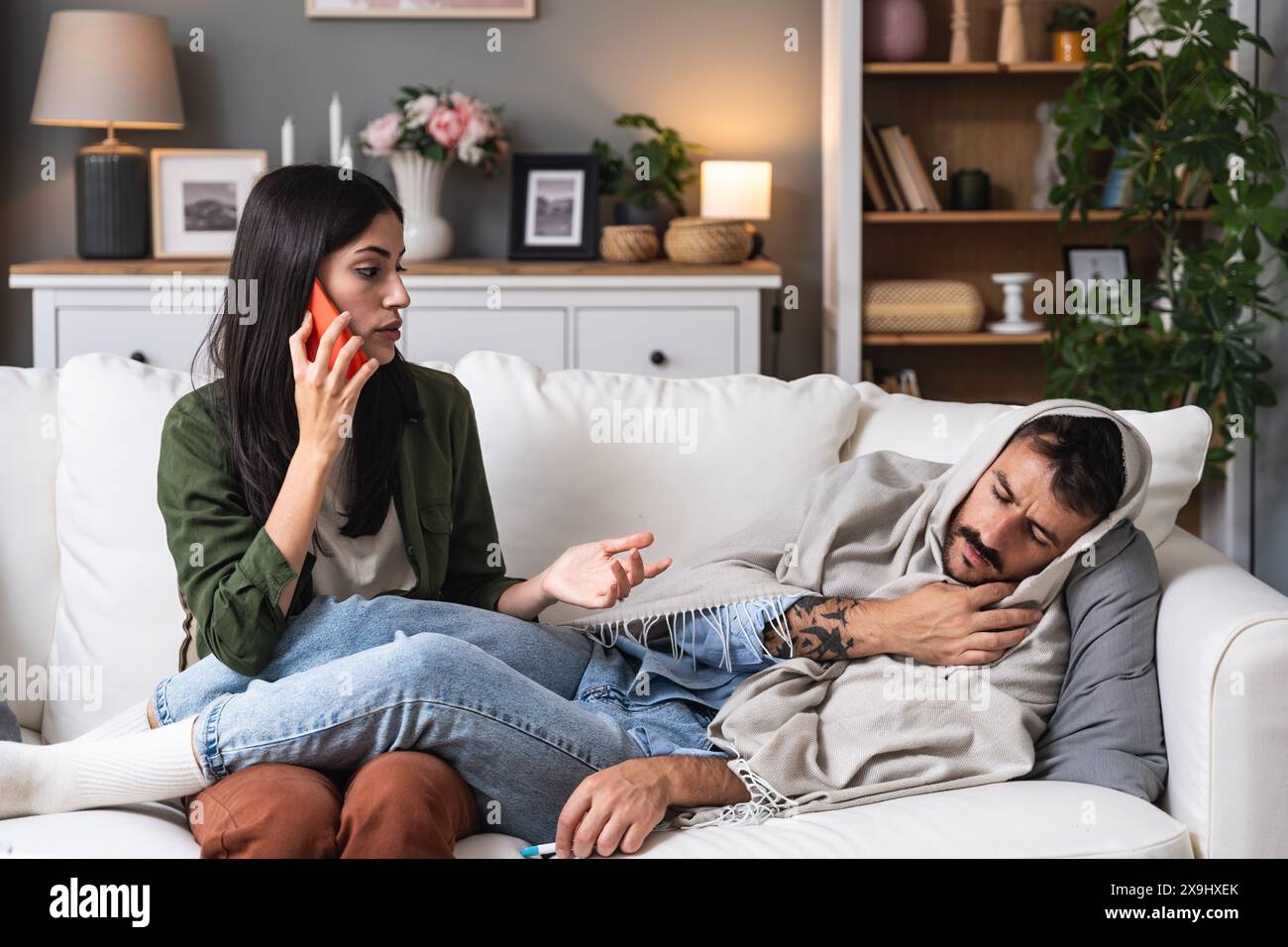 Young woman helping and treats her sick man at home who is wrapped in a ...