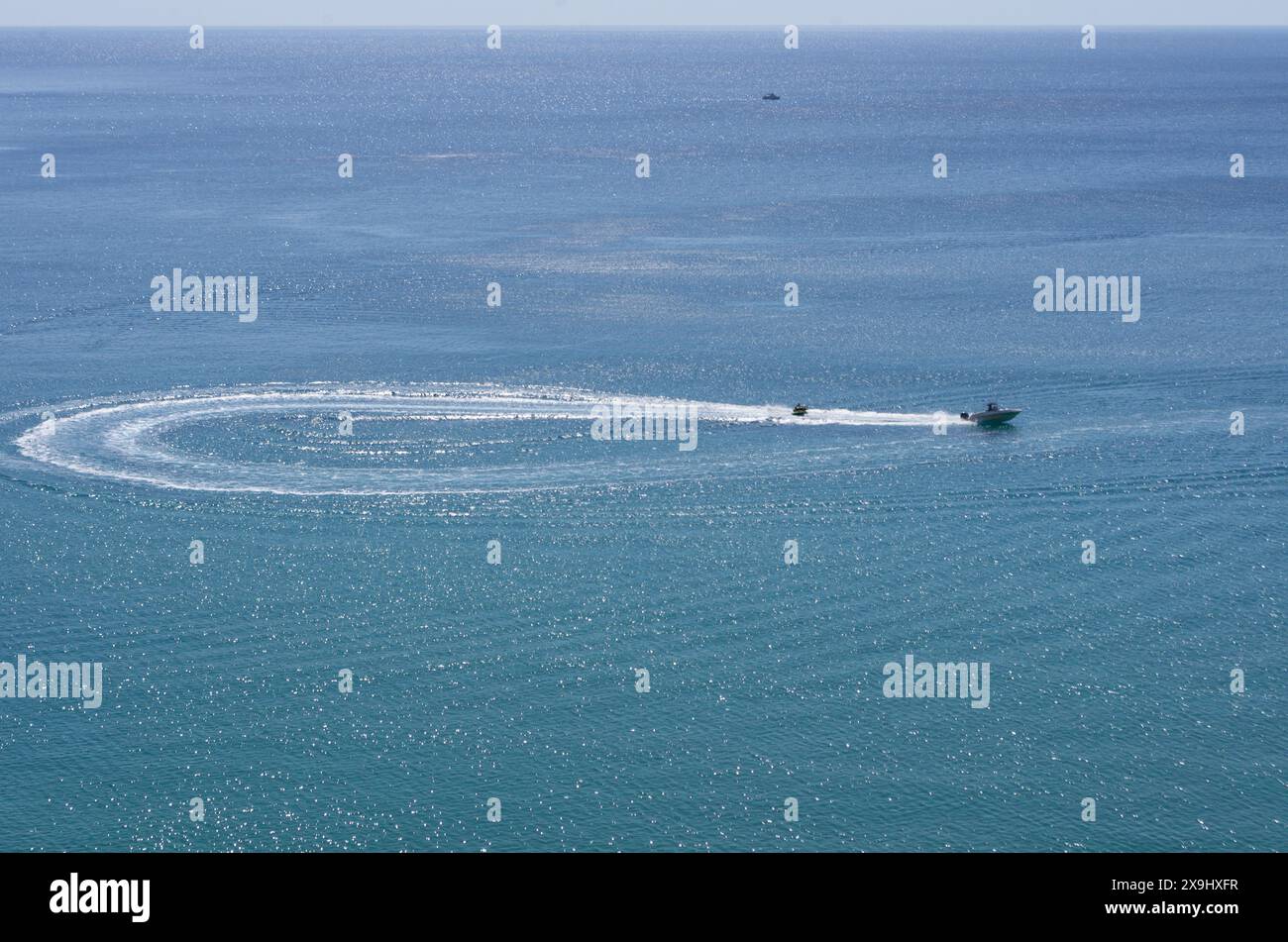 The boat rides tourists on tubing and completes a loop turn on the sea ...